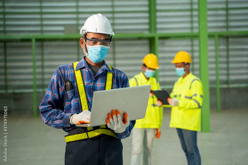 Warehouse worker wearing protective mask to Protect Against Covid-19 during the inspection in a ...