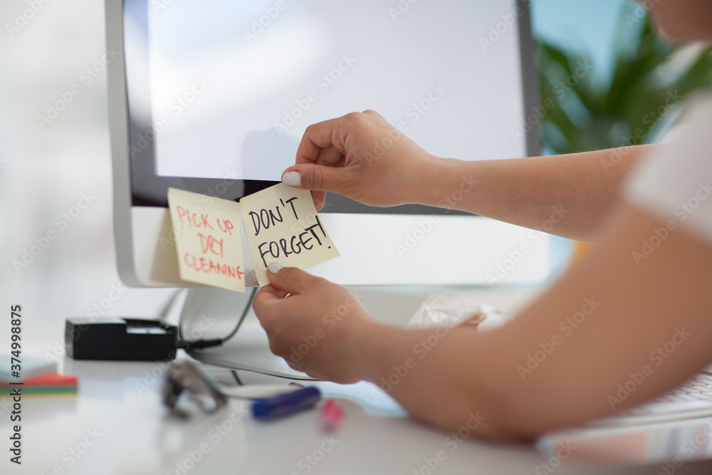 Woman sticking post it reminders on her desktop monitor. Stock Photo ...