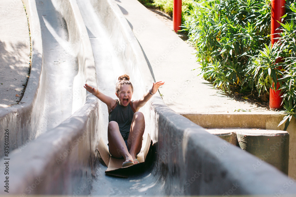 Fun loving girl sliding down cement slides. Stock Photo | Adobe Stock