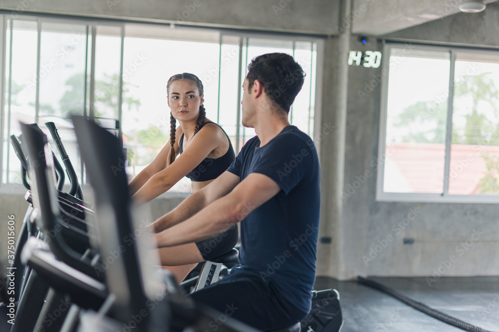 Male and female athletes talk about exercise, cycling in the gym. They ...