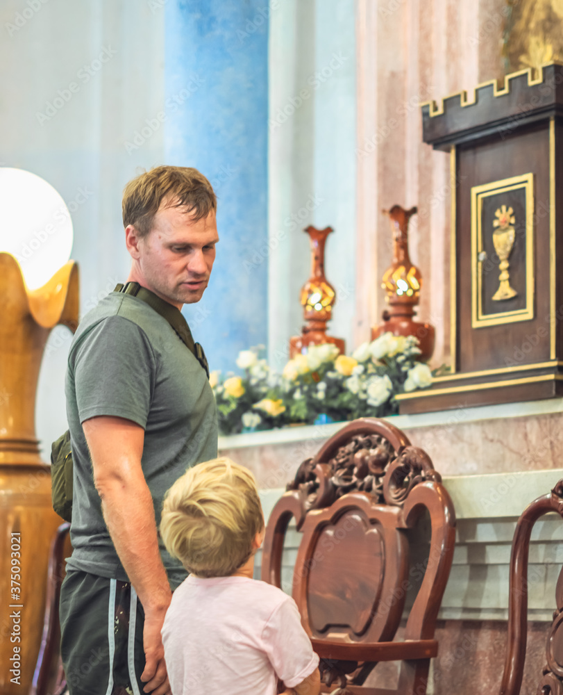Christian dad tells boy Bible stories standing near Saint Jesus statue ...