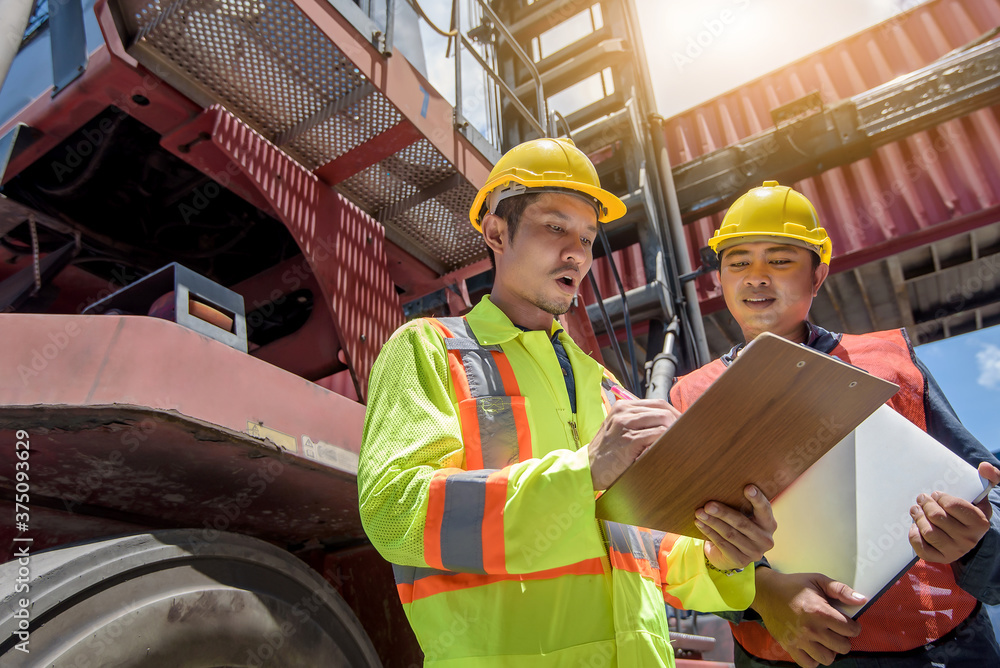 Engineer men wearing yellow hardhat standing near forklift cargo at the ...