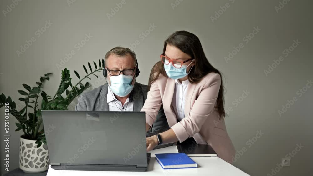 Office work during the covid-19 epidemic. Young employee helps a ...