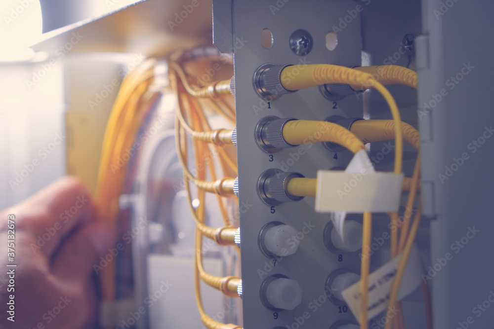 Hand of system engineer and fiber optic cable connected to enclosure ...
