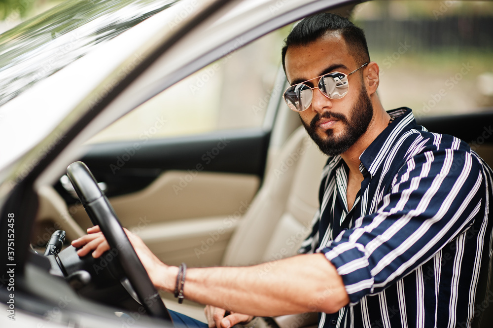 Successful arab man wear in striped shirt and sunglasses pose behind ...