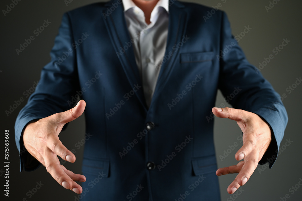 A man in a suit imitates holding an object. A man in a suit spreads his ...