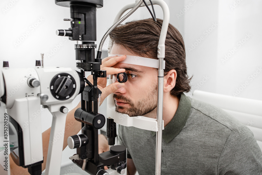 Adult man eyesight test with binocular slit-lamp. Checking retina of a ...