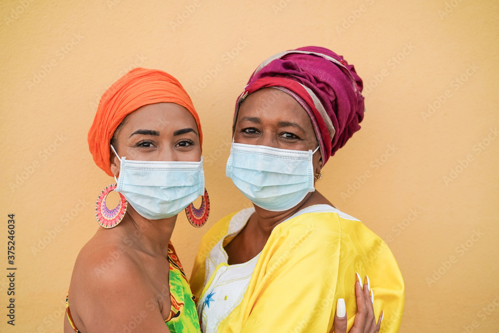African mother and daughter hug each other while wearing surgical face ...