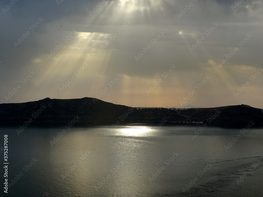 Natural Crepuscular rays above Nea Kameni island in Fira in Santorini ...