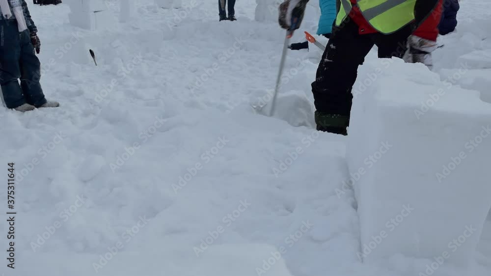Stockvideon Igloo. A man cuts out a snow block with a hacksaw to build ...