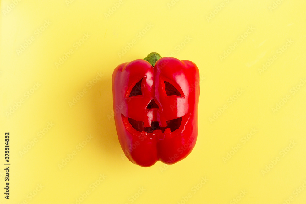 Scary face carved on red bell pepper for Halloween on yellow background ...