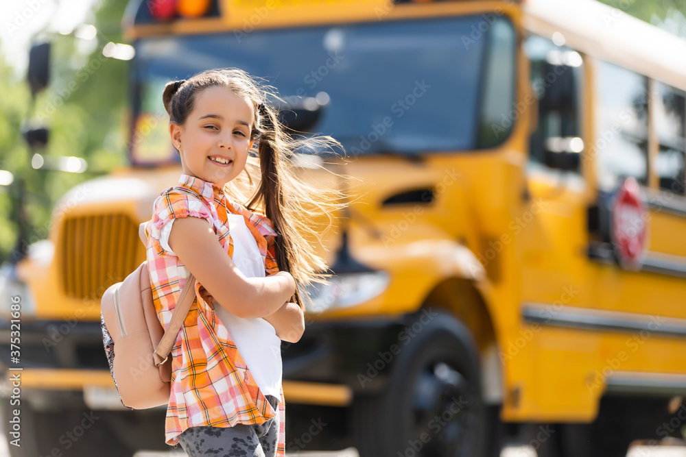 Little girl standing by a big school bus door with her backpack. Stock ...
