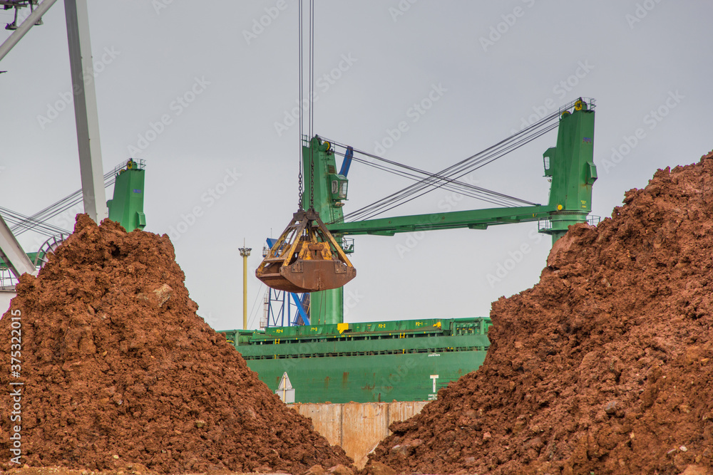 Understood grapple of a portal crane between stacks of cargo against ...