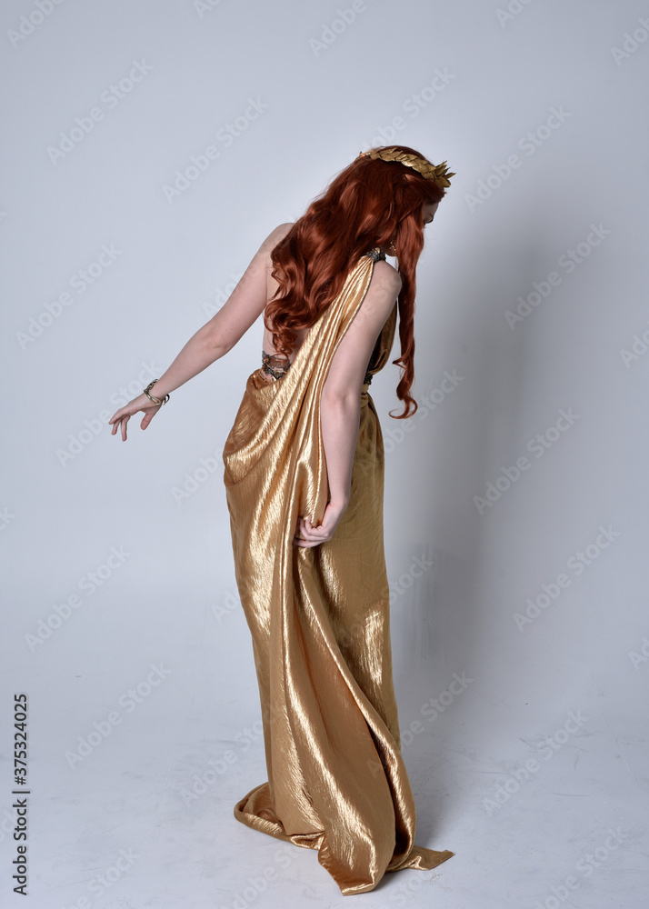 Full length portrait of girl with red hair wearing long grecian toga ...