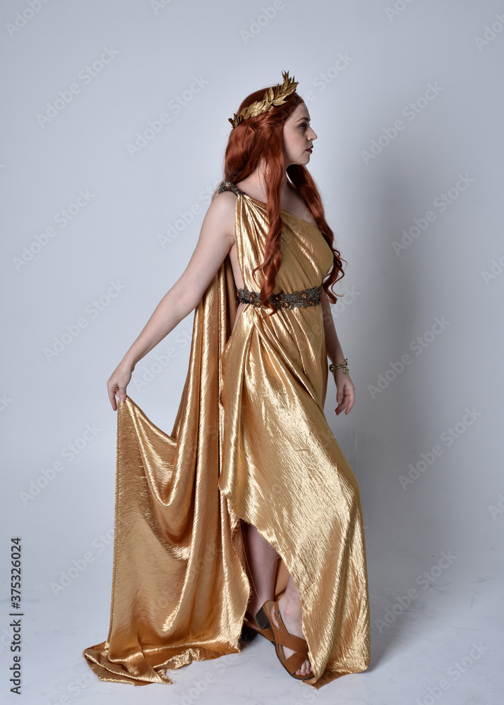 Full length portrait of girl with red hair wearing long grecian toga ...