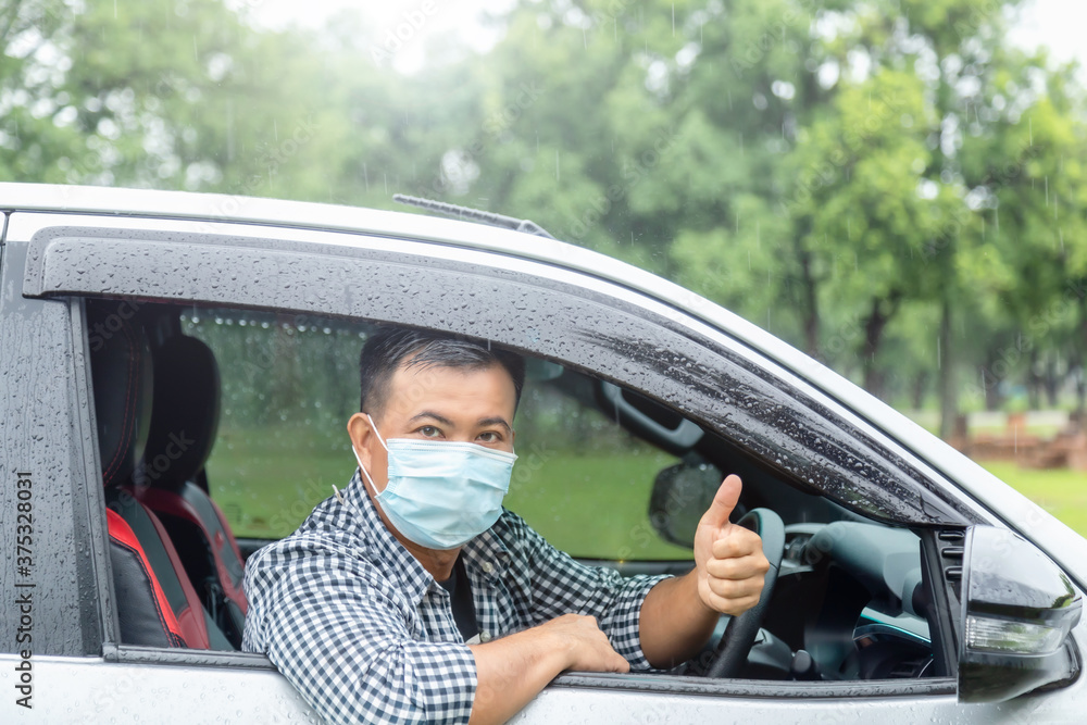 Asian people wearing mask is sitting in the car and thumbs up to camera ...