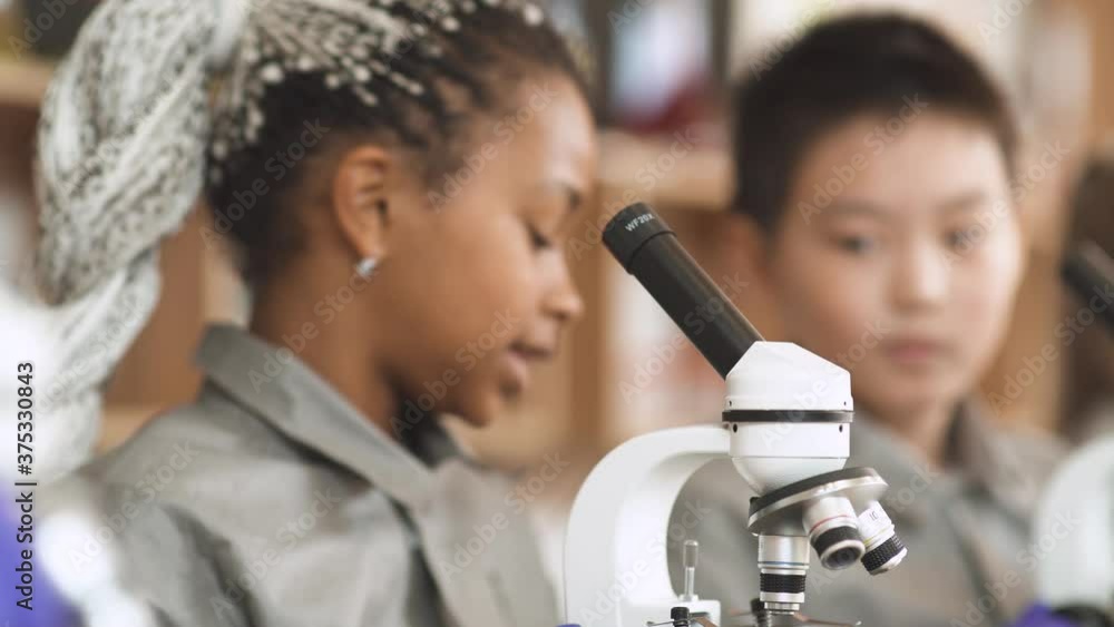 Lesson in a modern school, kids look at microscopes and communicate in ...
