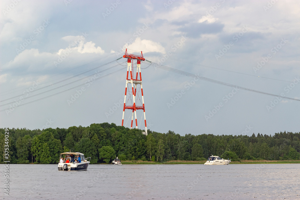Red-white High voltage tower over the lake. Electricity pylon,cables ...