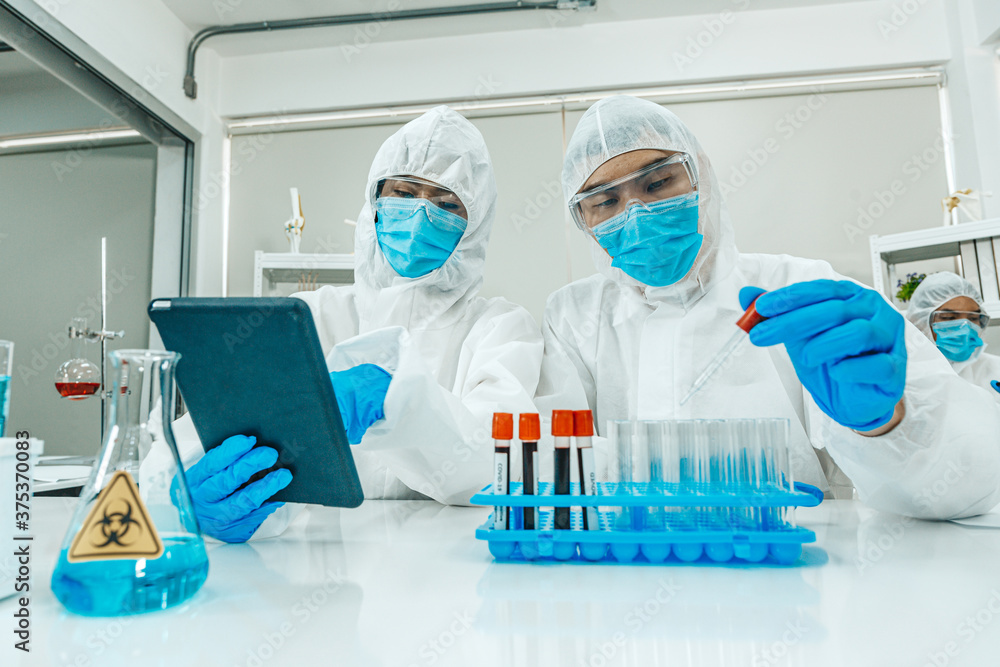 Two Scientists in PPE Suit working in Lab while Checking Result of ...