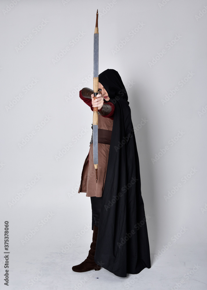 Full length portrait of girl with red hair wearing medieval archer ...