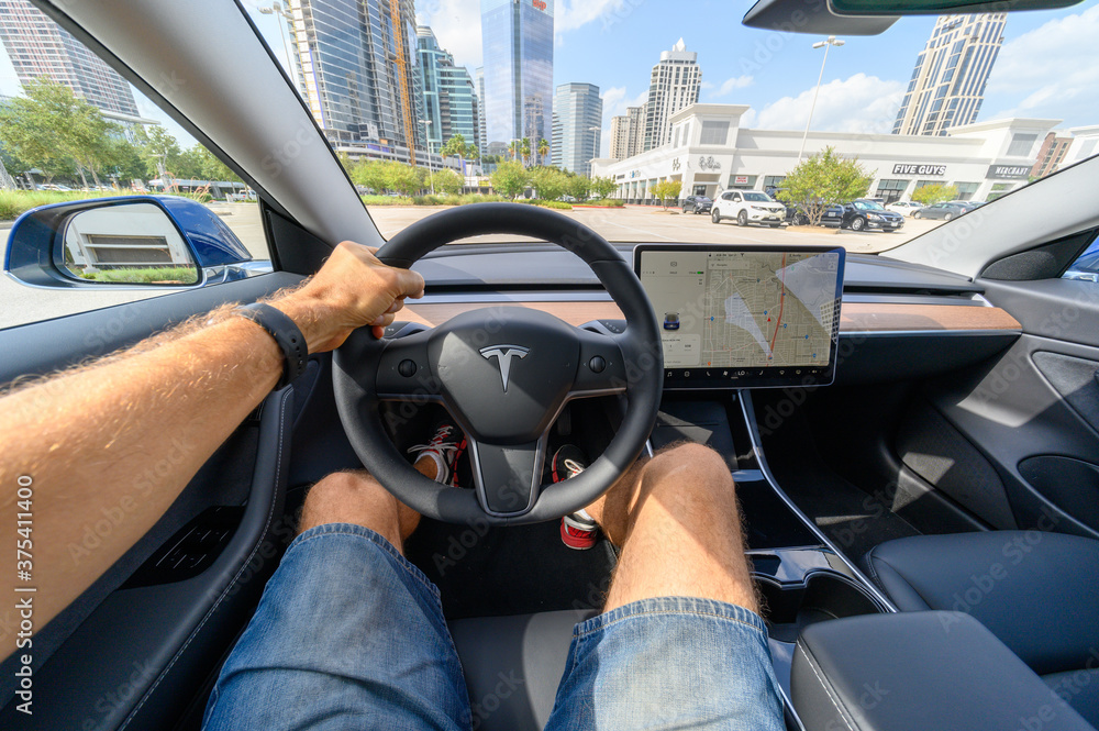 Person driving a new Tesla car. The interior of a long-range, all ...
