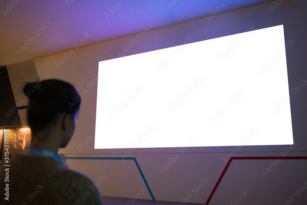 Woman looking at large wall blank interactive white display in dark ...