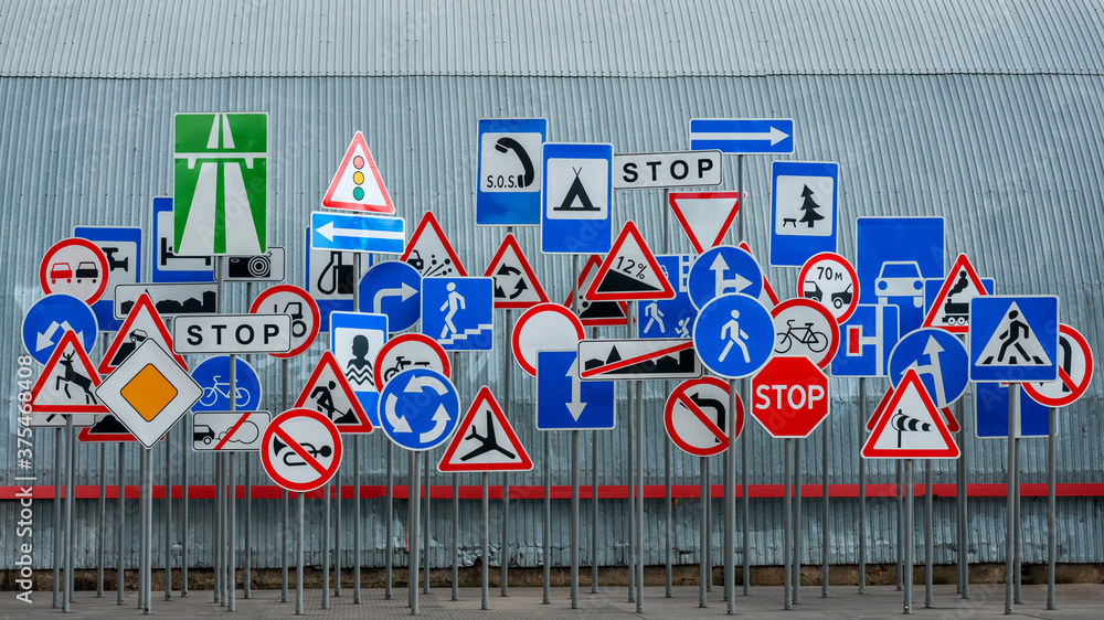 Many various road signs on grey corrugated metal background, horizontal ...