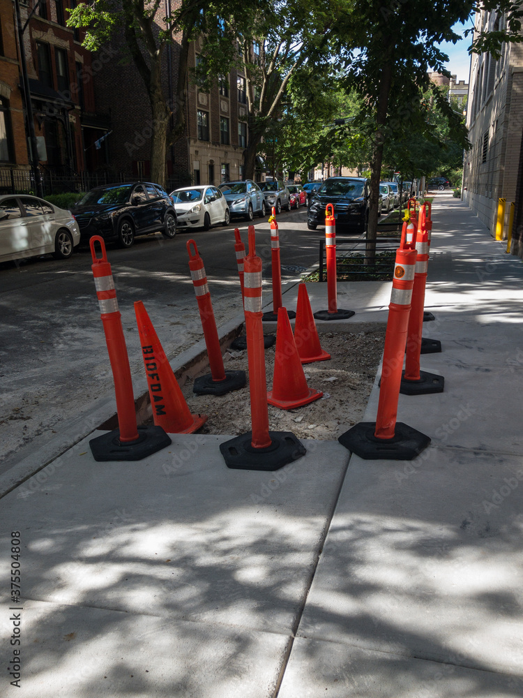 concrete construction on sidewalk protected by orange safety cones on ...