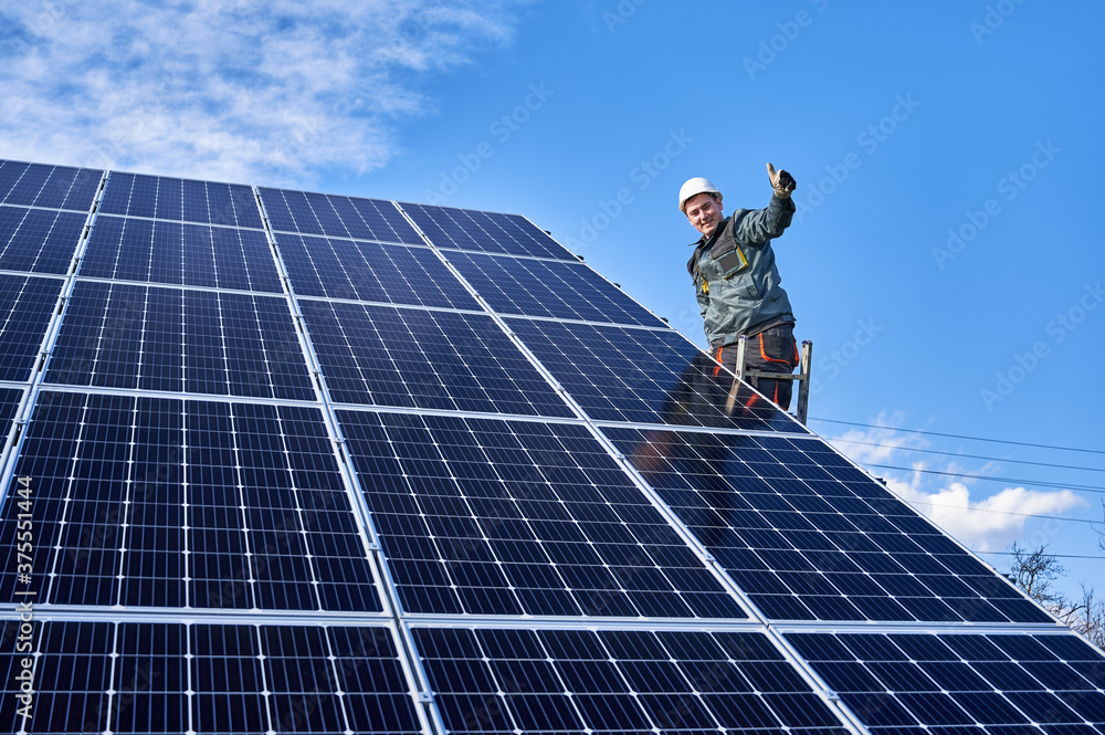 Smiling worker, installing solar batteries. Male engineer standing on ...