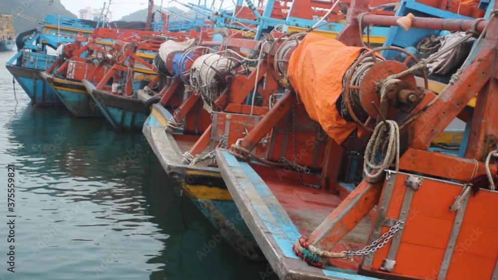 Fishing trawler at the pier lined up side to side (stern and winch ...