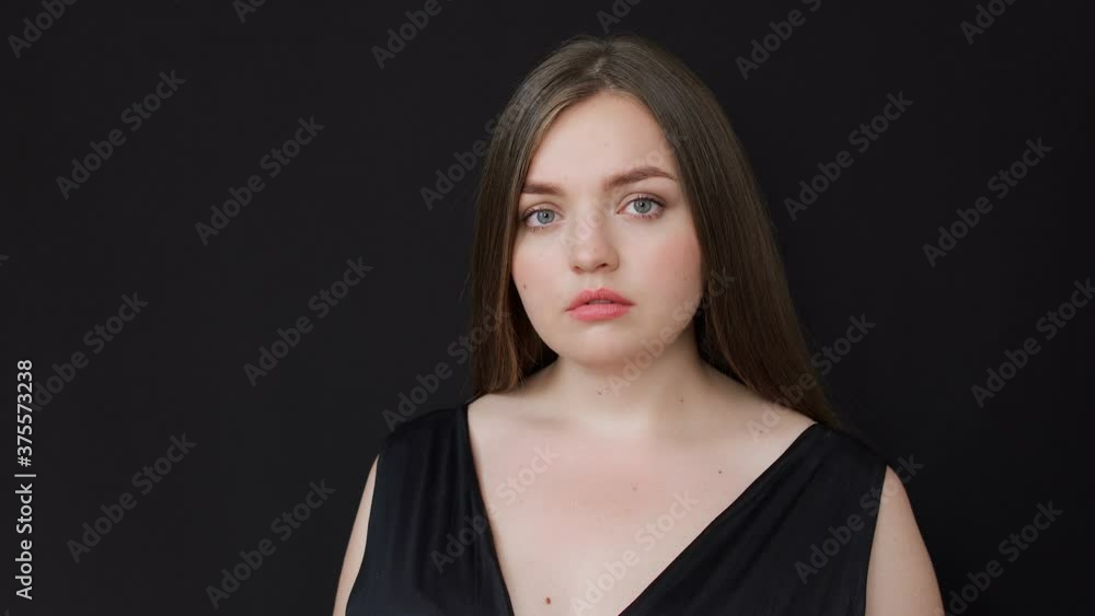 Close up face upset pump girl against black background, shy of her ...