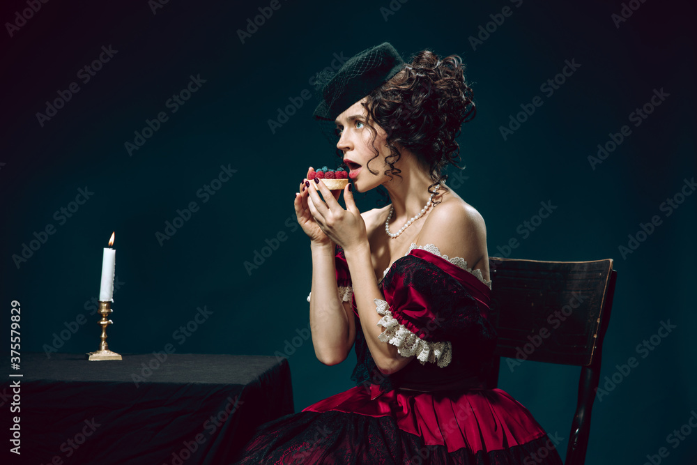 Forbidden sweets. Young woman as Anna Karenina isolated on dark blue ...