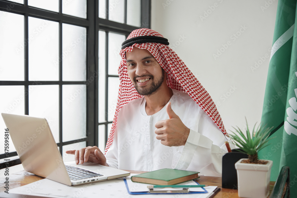 Happy Arab businessman smile and thumb up while working on laptop ...