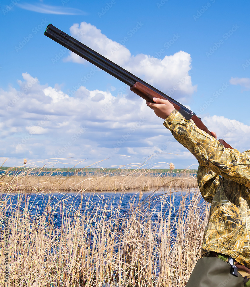 young male with shotgun sitting on grass, have rest after hunting ...