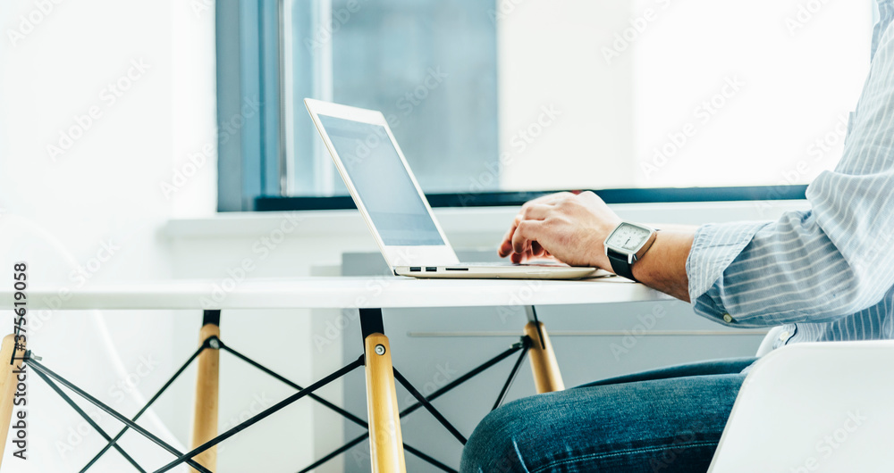 Man working on laptop computer in modern bright corporate office ...