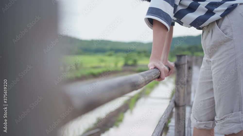Young woman resting her arms on wooden bridge hand rail, travel journey ...
