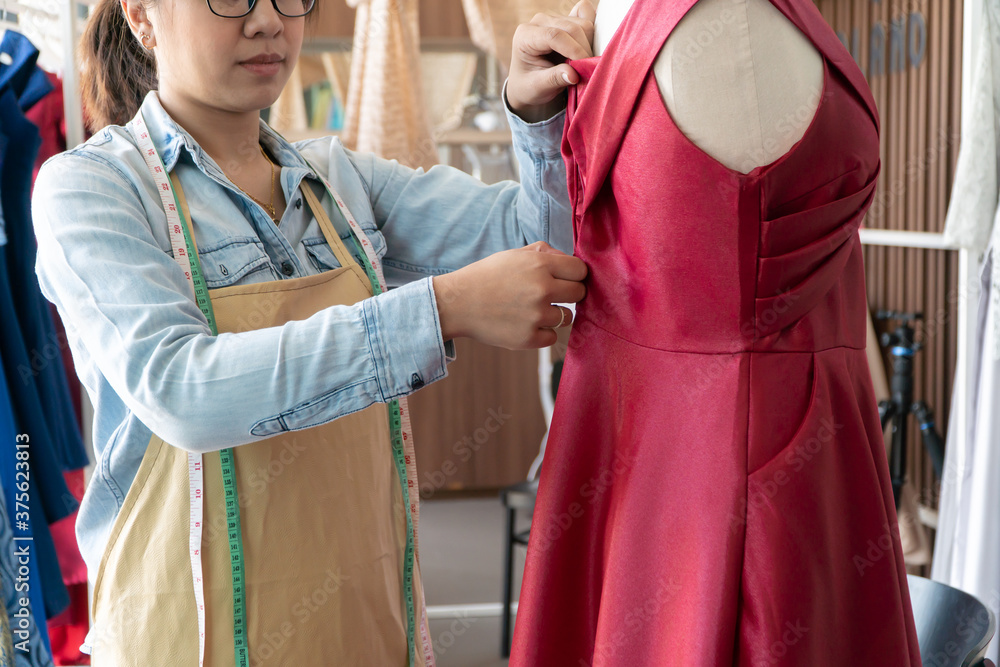 Asian woman dressmaker fashion designer measuring size of mannequin in ...