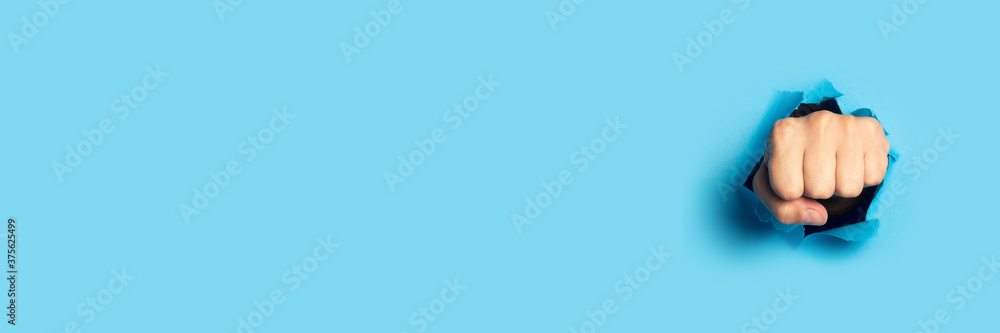 Male fist punches a wall on a blue background. Banner. Breakout gesture ...