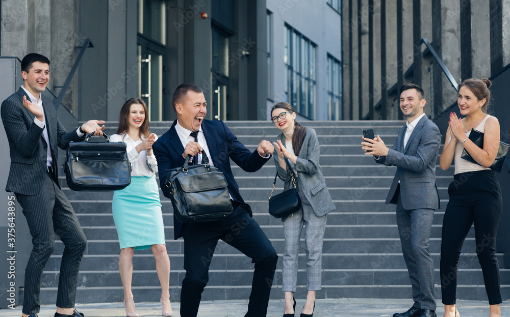 Overjoyed excited male leader and carefree business team dance together ...