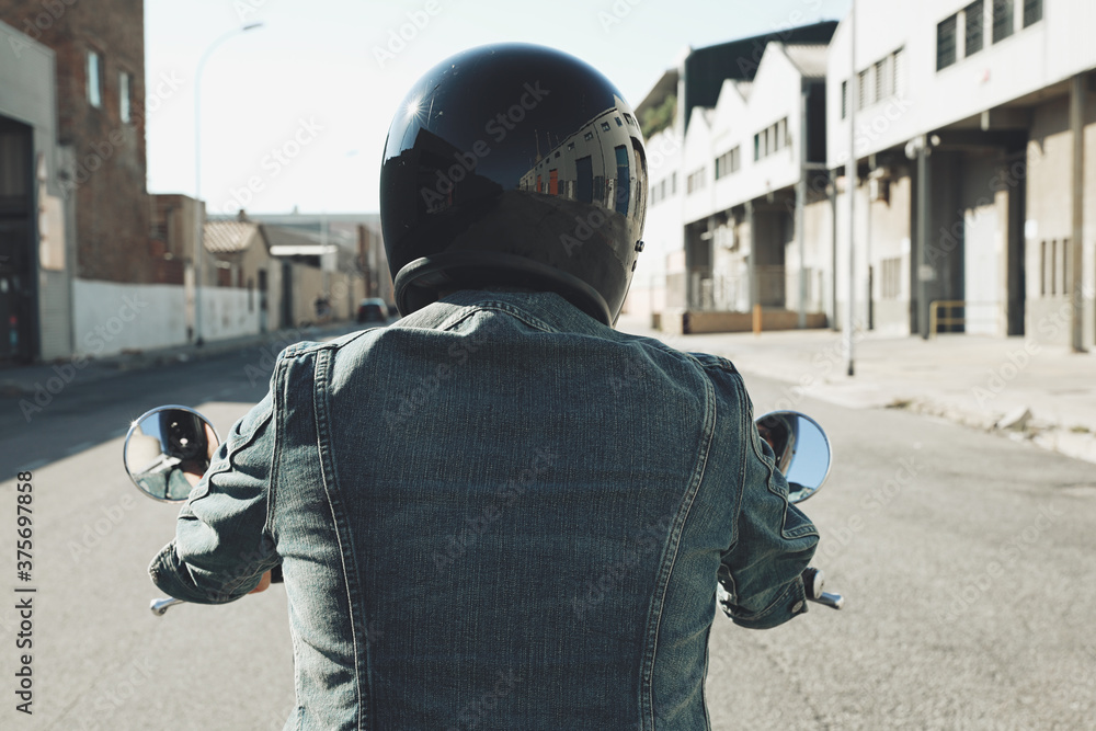 Back side of biker staying with unknown big chopper bike on road ...