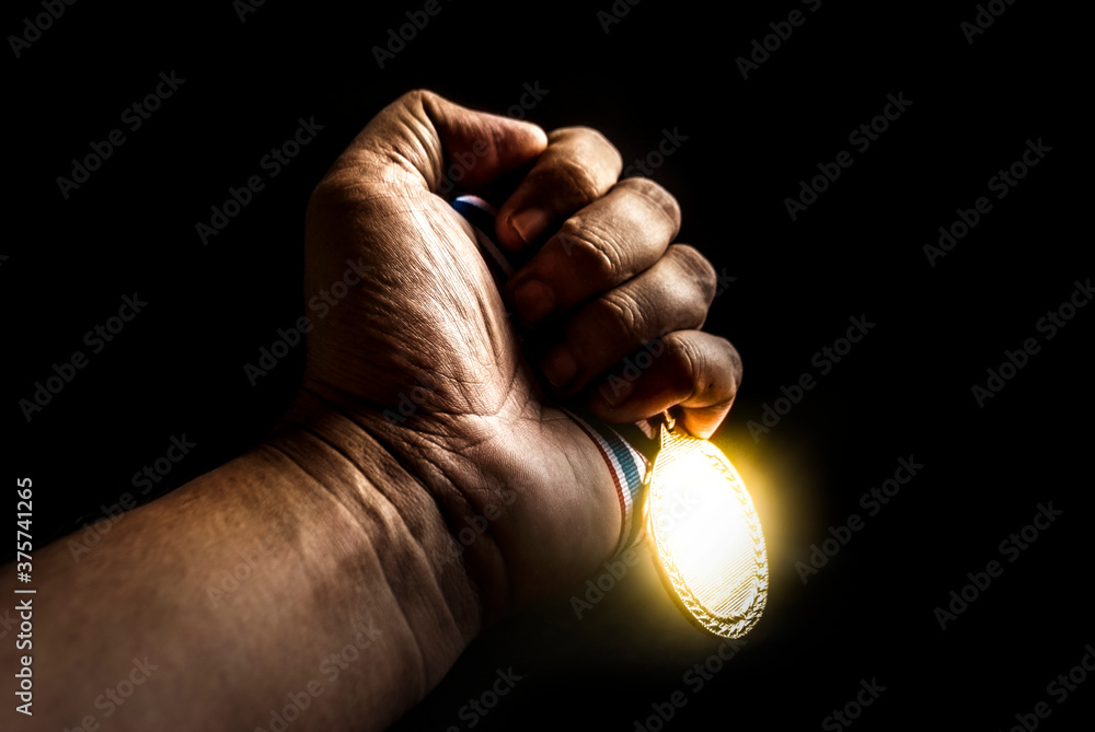 The medal in the hand. Black background. Stock Photo | Adobe Stock