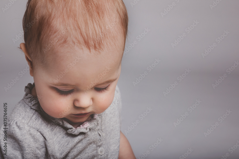 Cute baby girl looking down on solid background Stock Photo | Adobe Stock