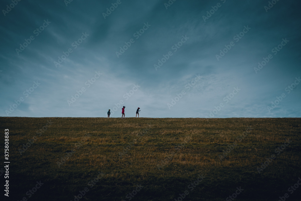 Drei Kinder laufen hintereinander auf dem Grad eines Deichs in ...