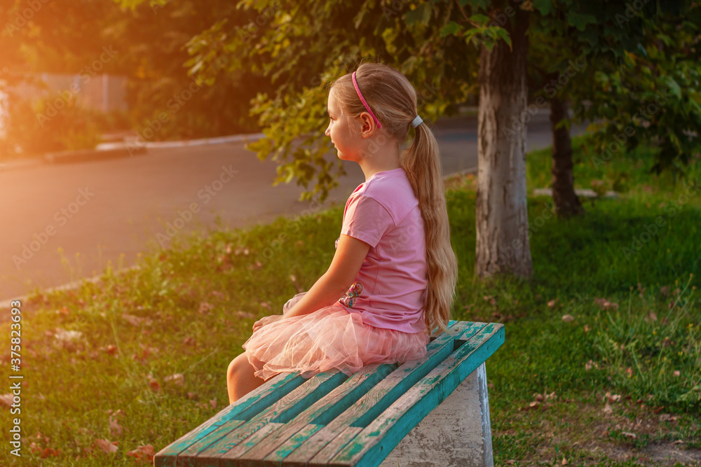 Cheerful little girl with long blonde hair in pink tulle skirt sitting ...