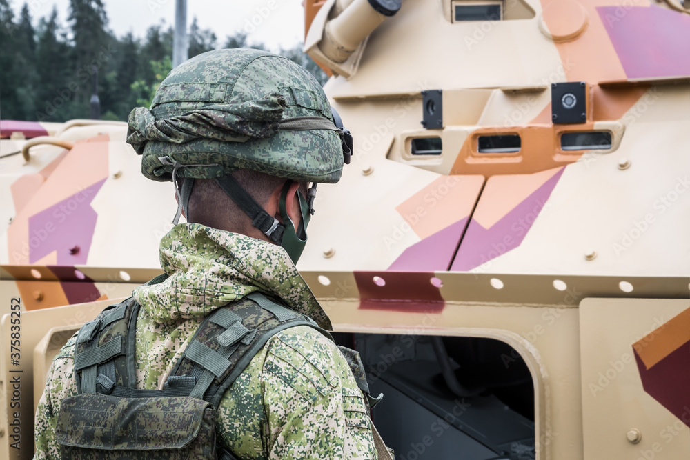 soldier in full armor stands next to military equipment. Modern weapons ...