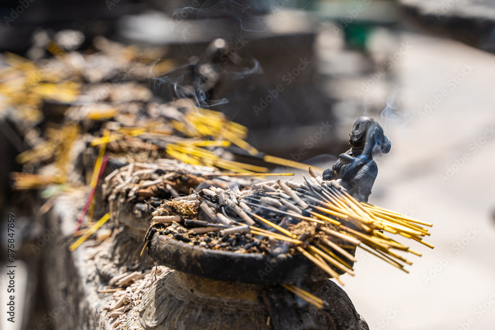Small praying human figures with a lot of incense sticks around ...