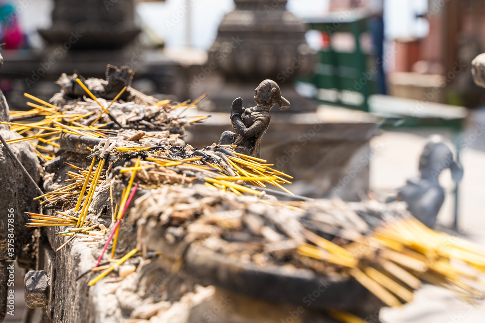 Small praying human figures with a lot of incense sticks around ...
