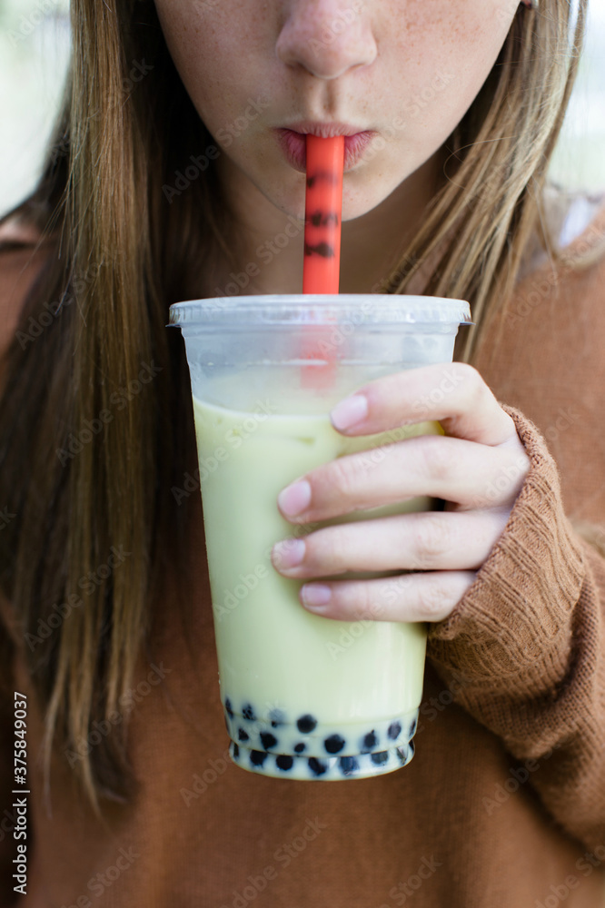 Teen girl drinking a bubble tea or Boba drink Stock Photo | Adobe Stock