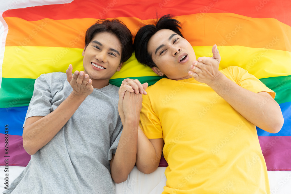 asian two men homosexual couple lying on the rainbow flag, holding ...