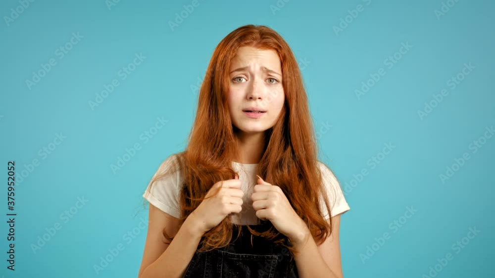 Portrait of young unpleasantly surprised and shocked girl on blue ...